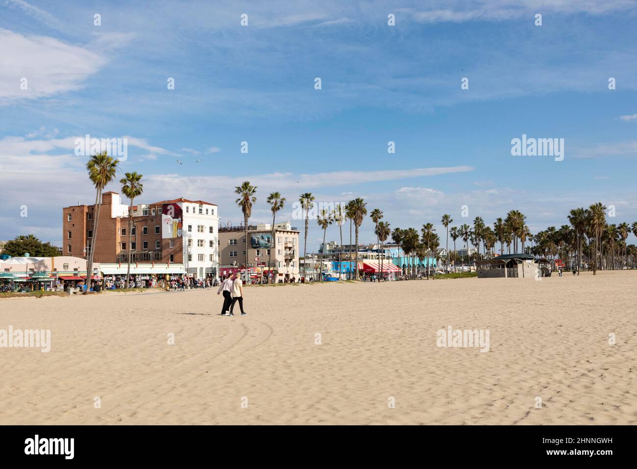 people enjoy scenic beach promenade with palms and colorful houses at ...