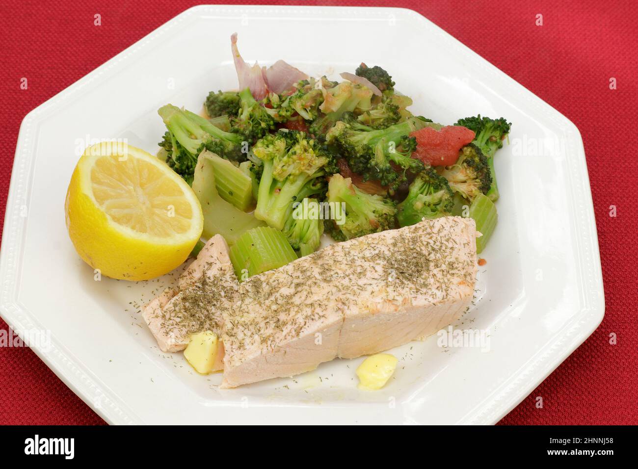 Farmed salmon fillet with dill butter and mixed vegetables on a white ...