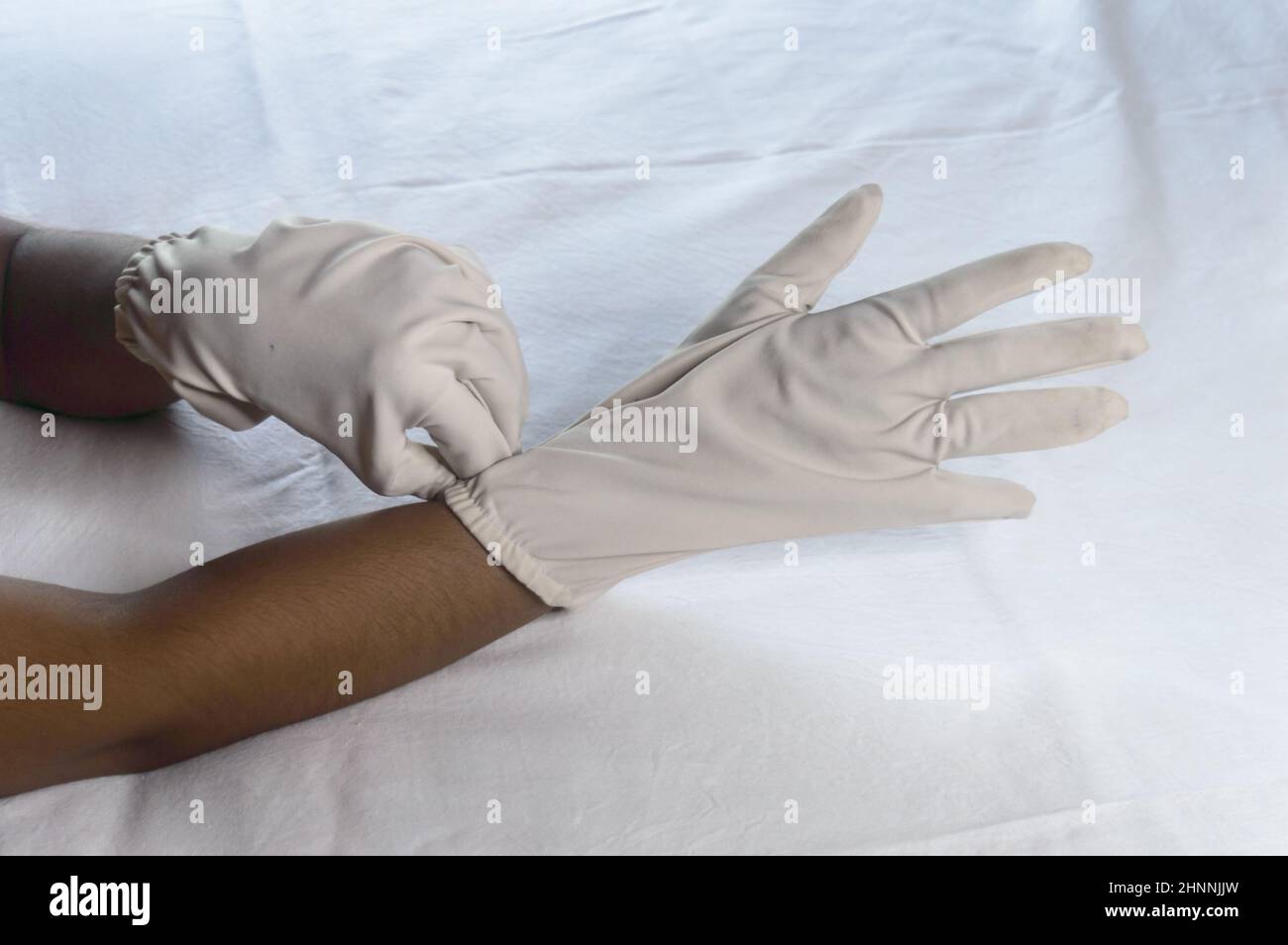 Hand Wearing Disposable Gloves against white background. High angle ...