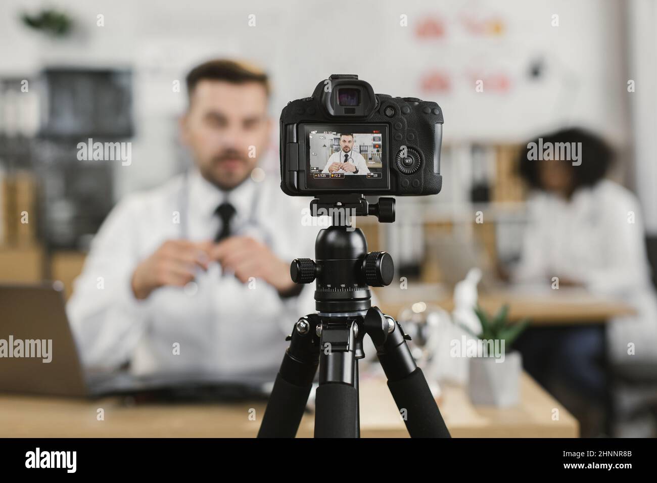 Competent medical worker in uniform doing live streaming while sitting ...