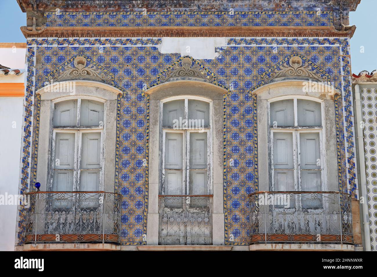 Blue and yellow tile facade-old abandoned townhouse-closed balconies ...