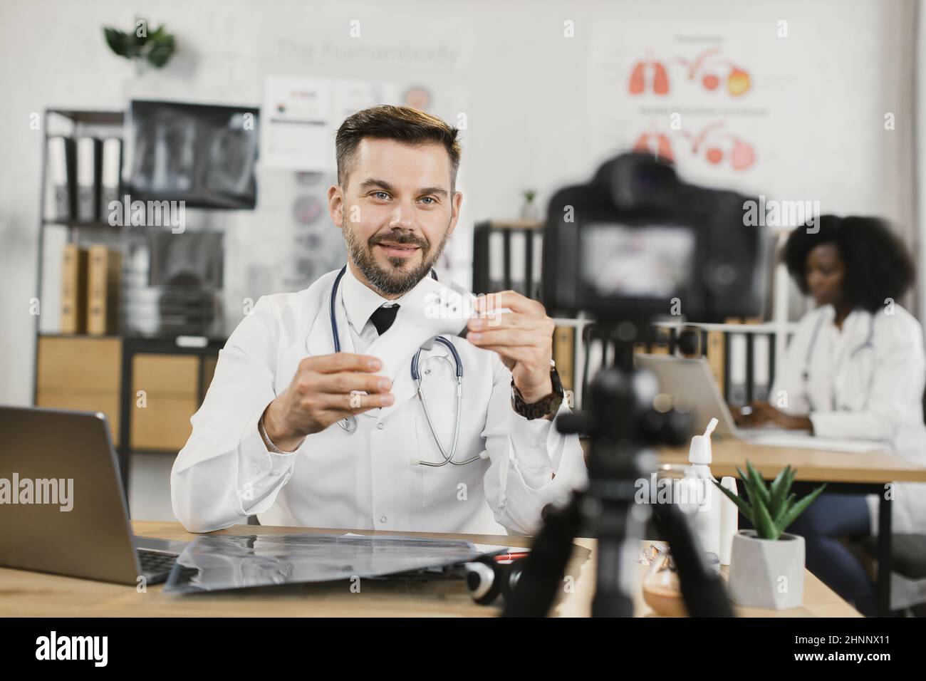 Caucasian medical worker sitting at desk with electronic thermometer in ...