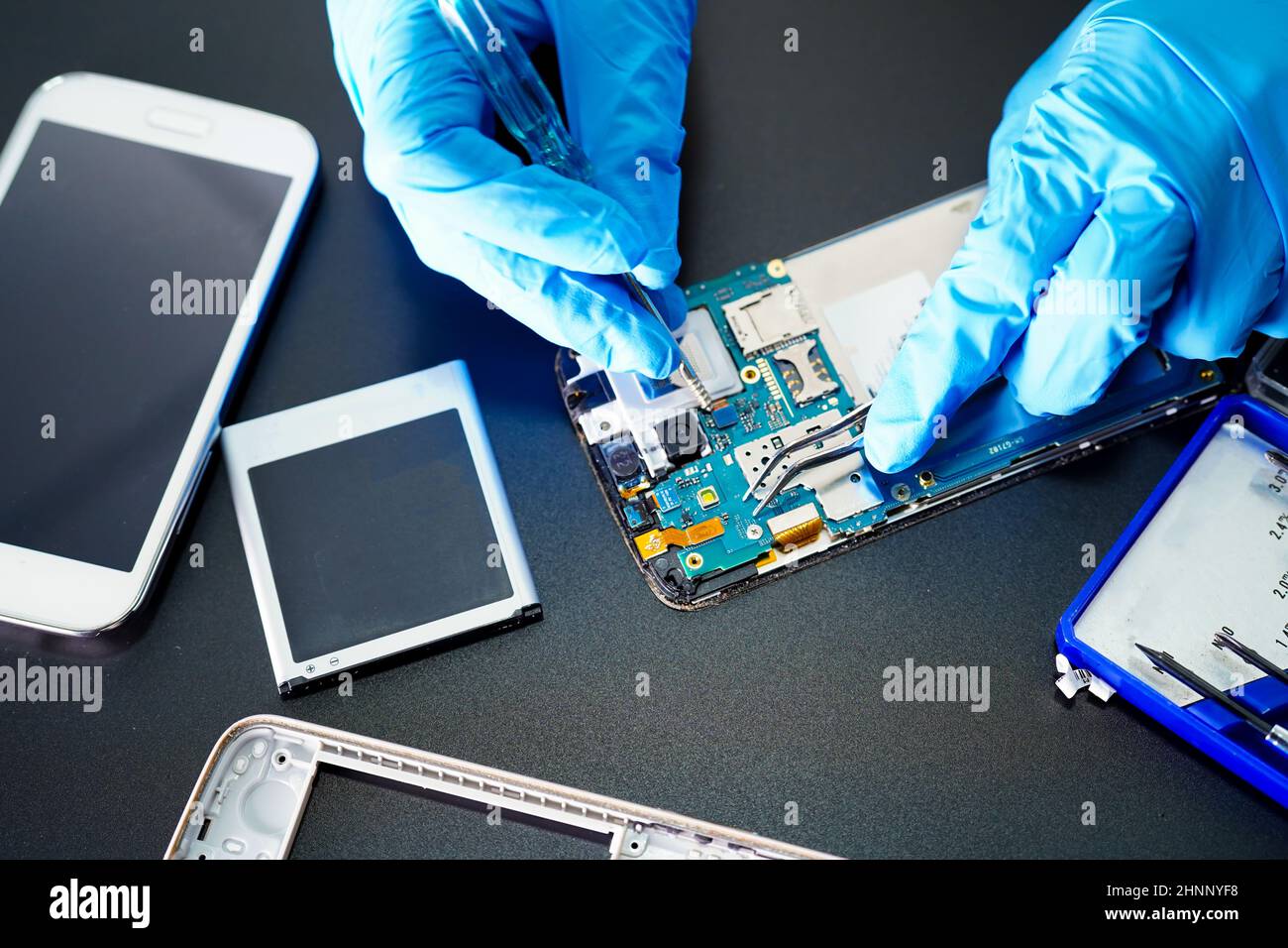 Technician repairing inside of mobile phone by soldering iron ...