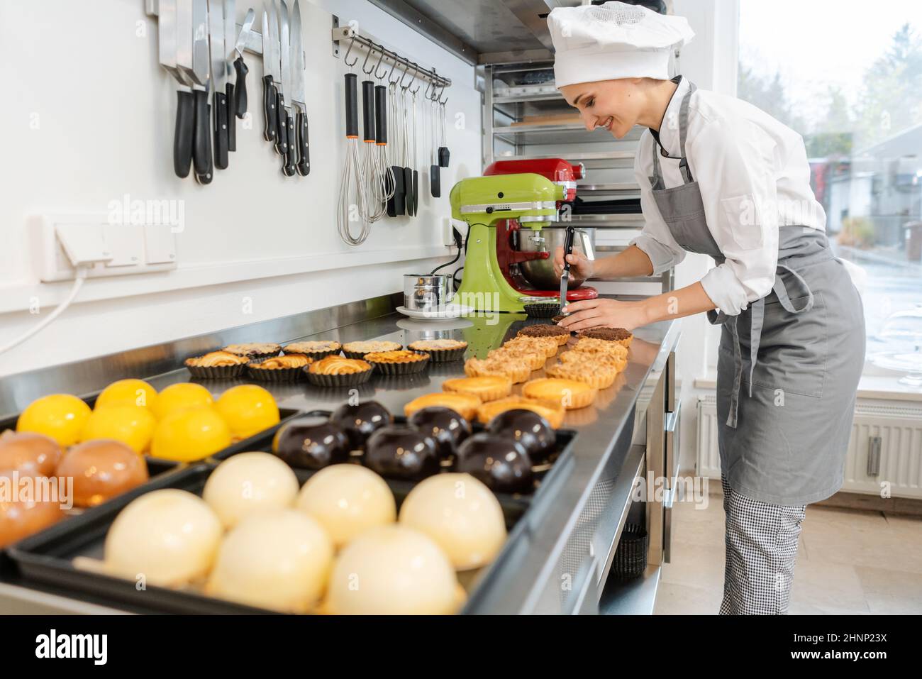 Confectioner working on lots of different sweets and desserts in her ...