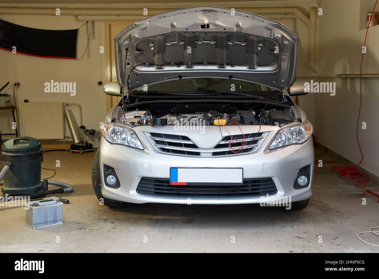 Car in a small repair shop garage with open hood, engine diagnostics ...