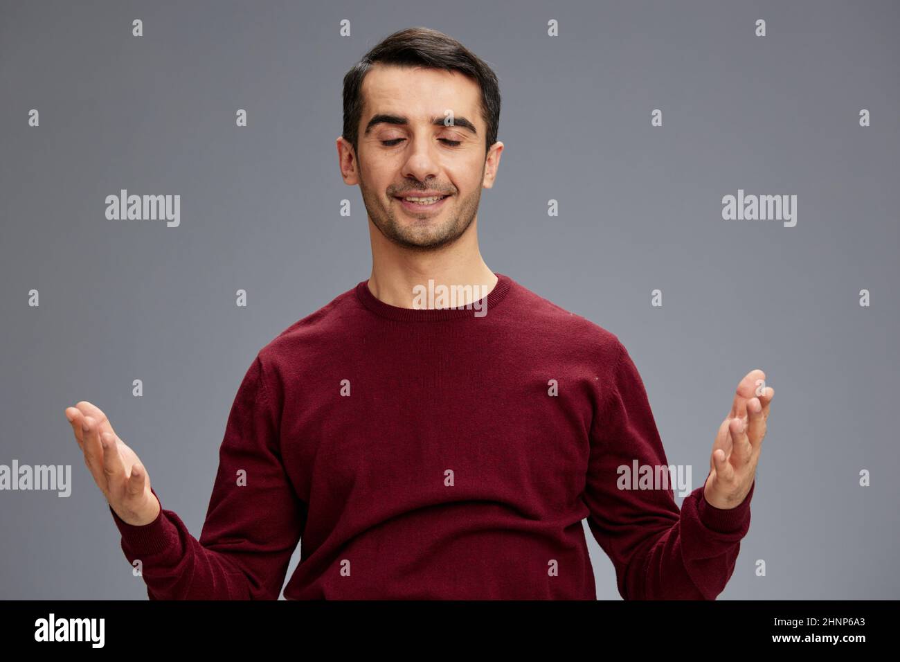 successful man with closed eyes in a sweater posing hand gesture ...