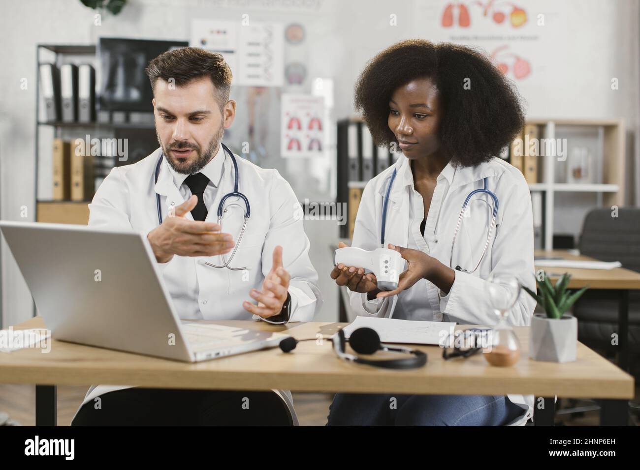 Multiracial male and female doctors using modern laptop for online ...