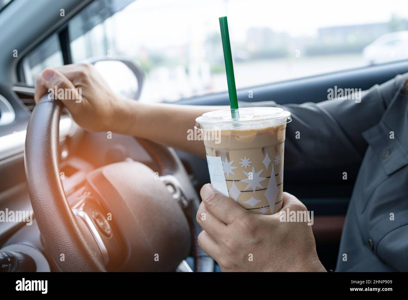 Asian lady holding ice coffee in car dangerous and risk an accident ...