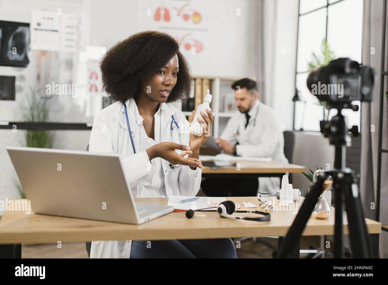 Qualified african female doctor in lab coat sitting at desk and ...
