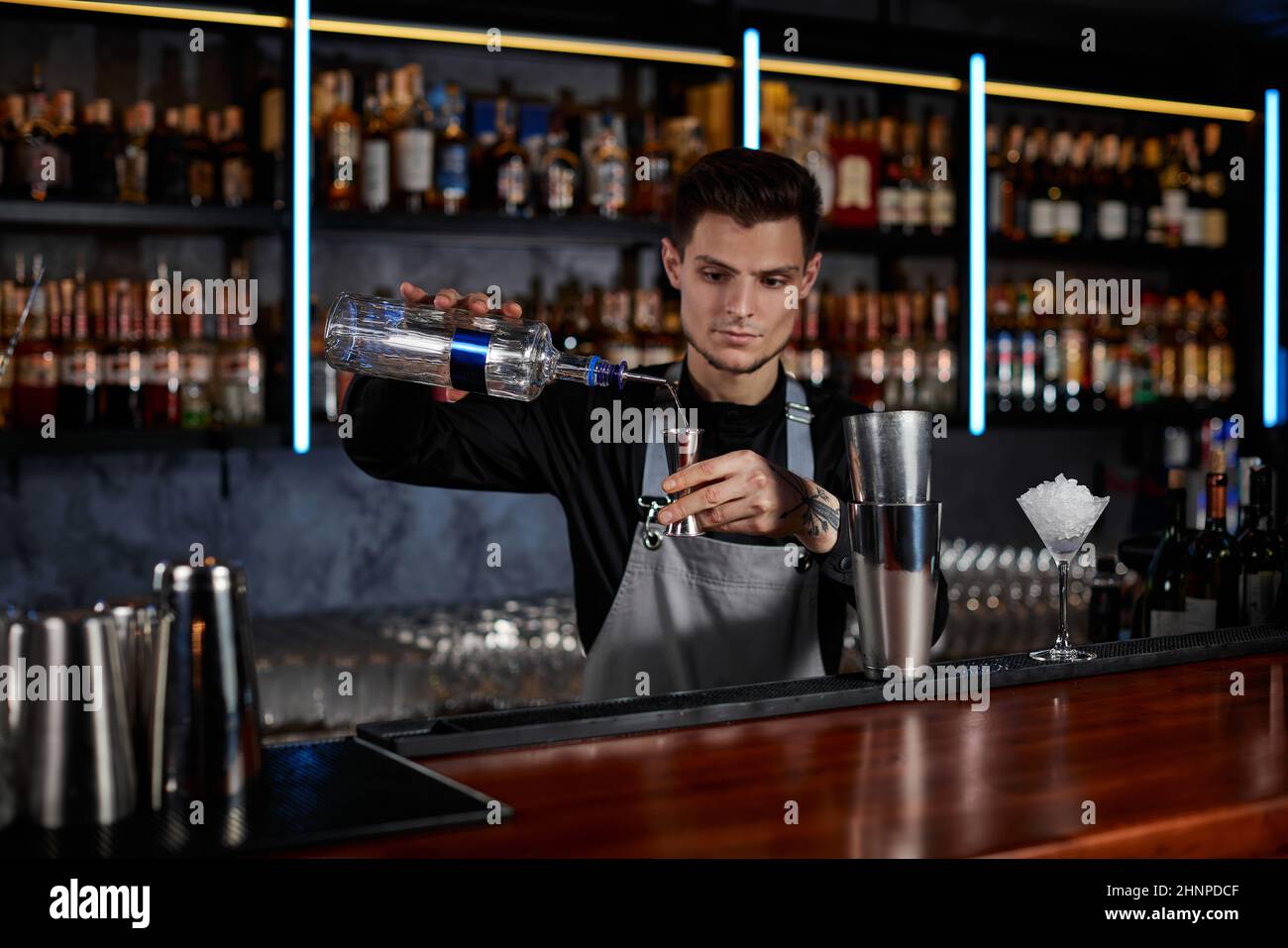 Bartender in apron adds ingredient to shaker Stock Photo - Alamy