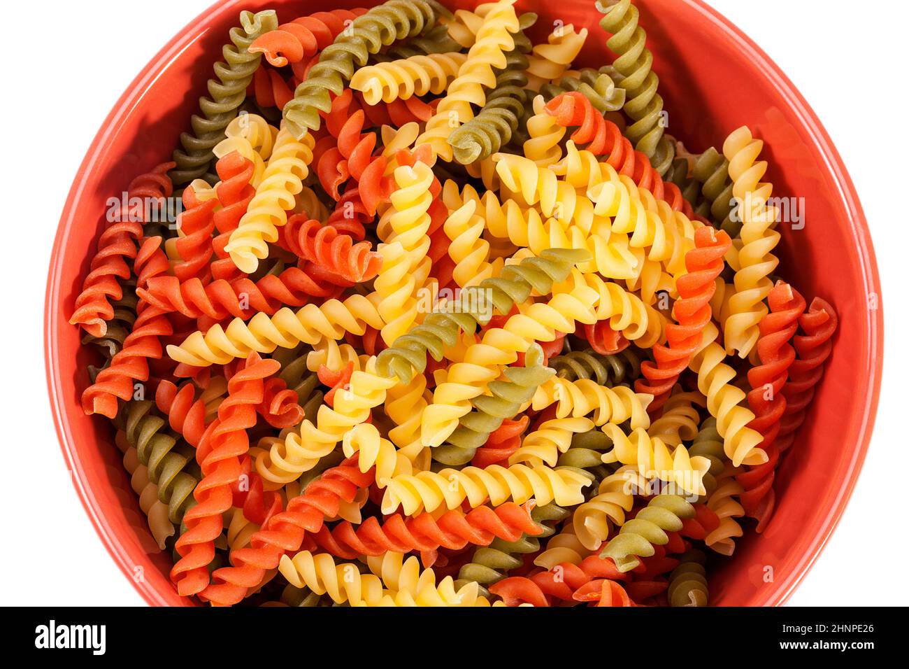 Spiral colored pasta in orange bowl, white background Stock Photo - Alamy