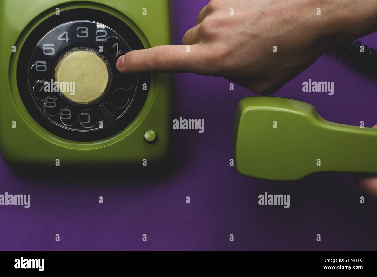 Hand dialing a number on a classic phone with round dial. vintage green ...