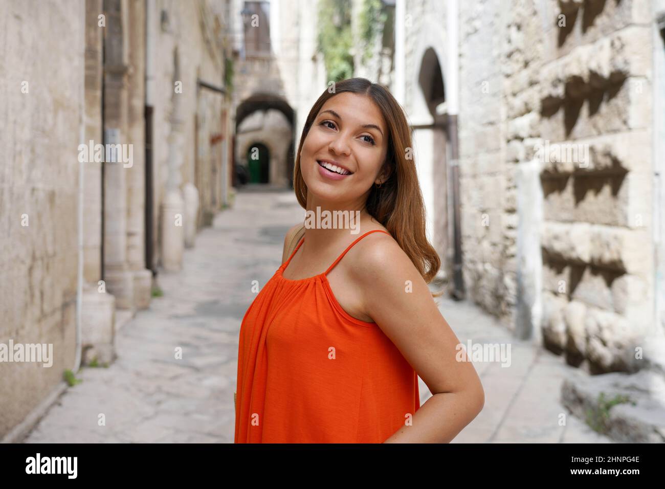 Close up outdoor portrait of beautiful woman in orange dress turn ...
