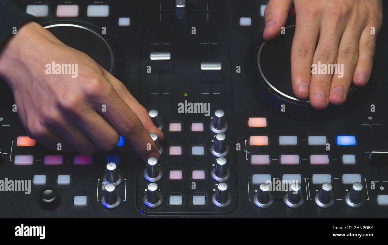 DJ plays music. sound mixer controller with knobs and sliders close up ...