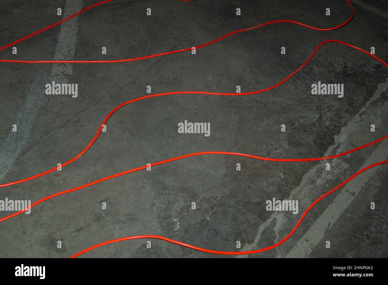 Red electric power cable. red wire lies on the ground. mess on cement ...