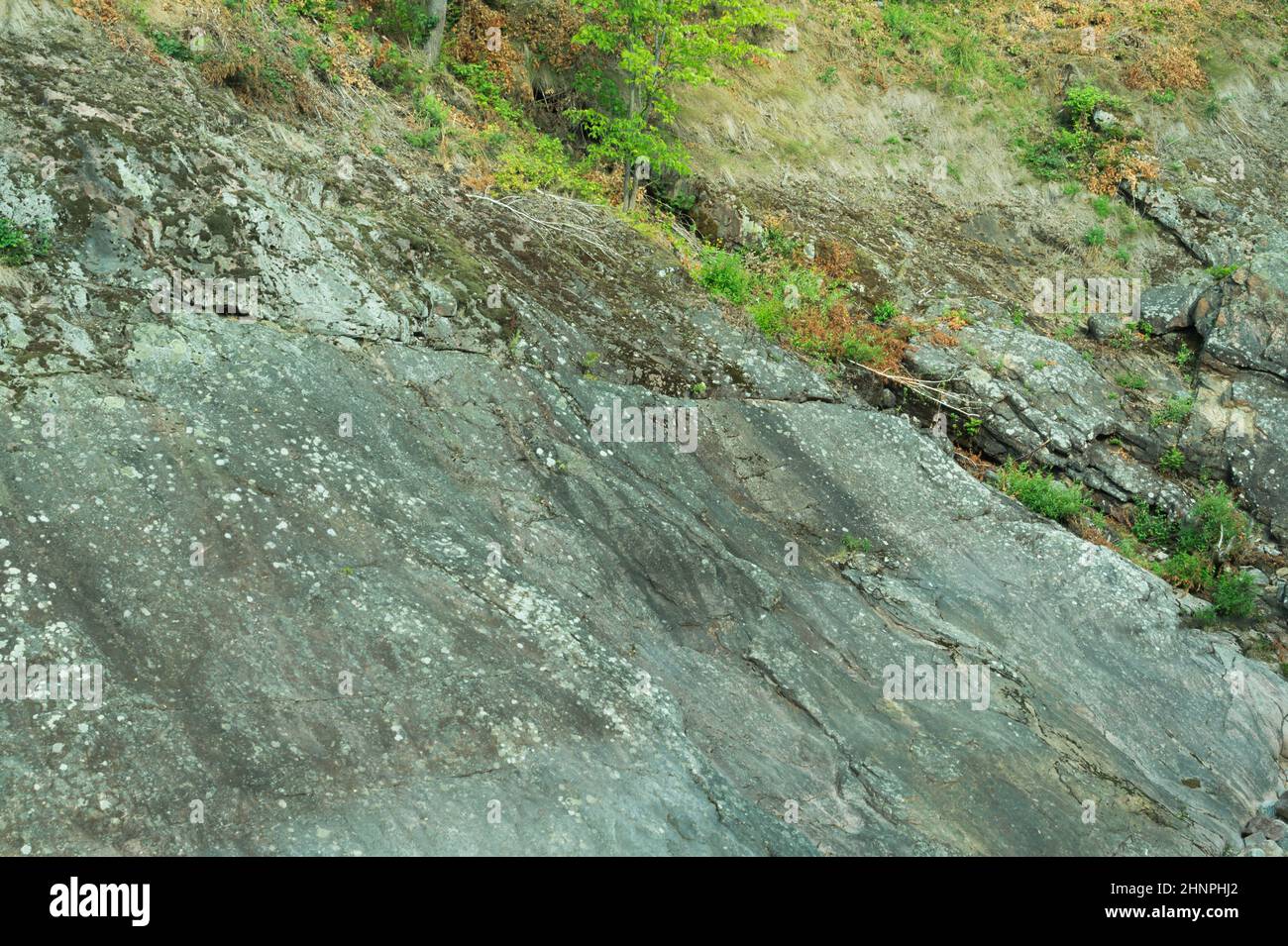 Rock of layered stone overgrown with grass and moss. texture of stone ...