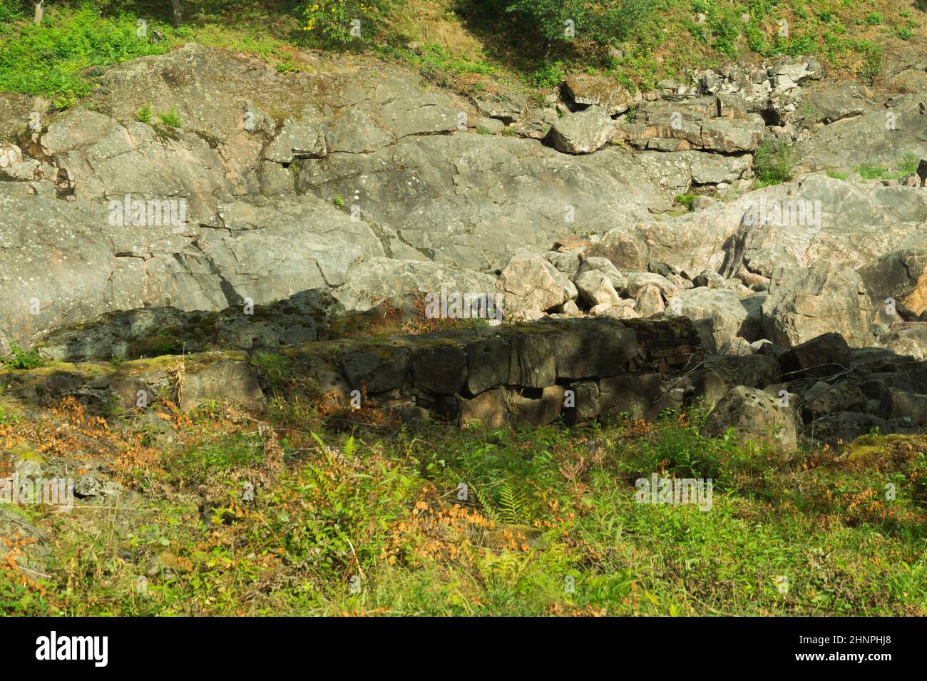 Rock of layered stone overgrown with grass and moss. texture of stone ...