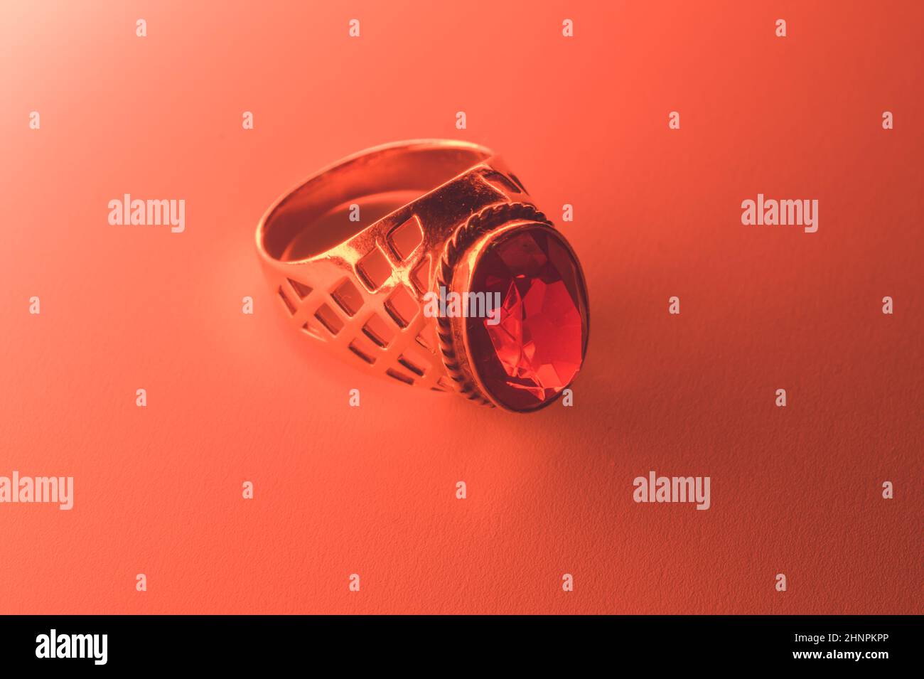 Golden ring with ruby under red light background Stock Photo - Alamy