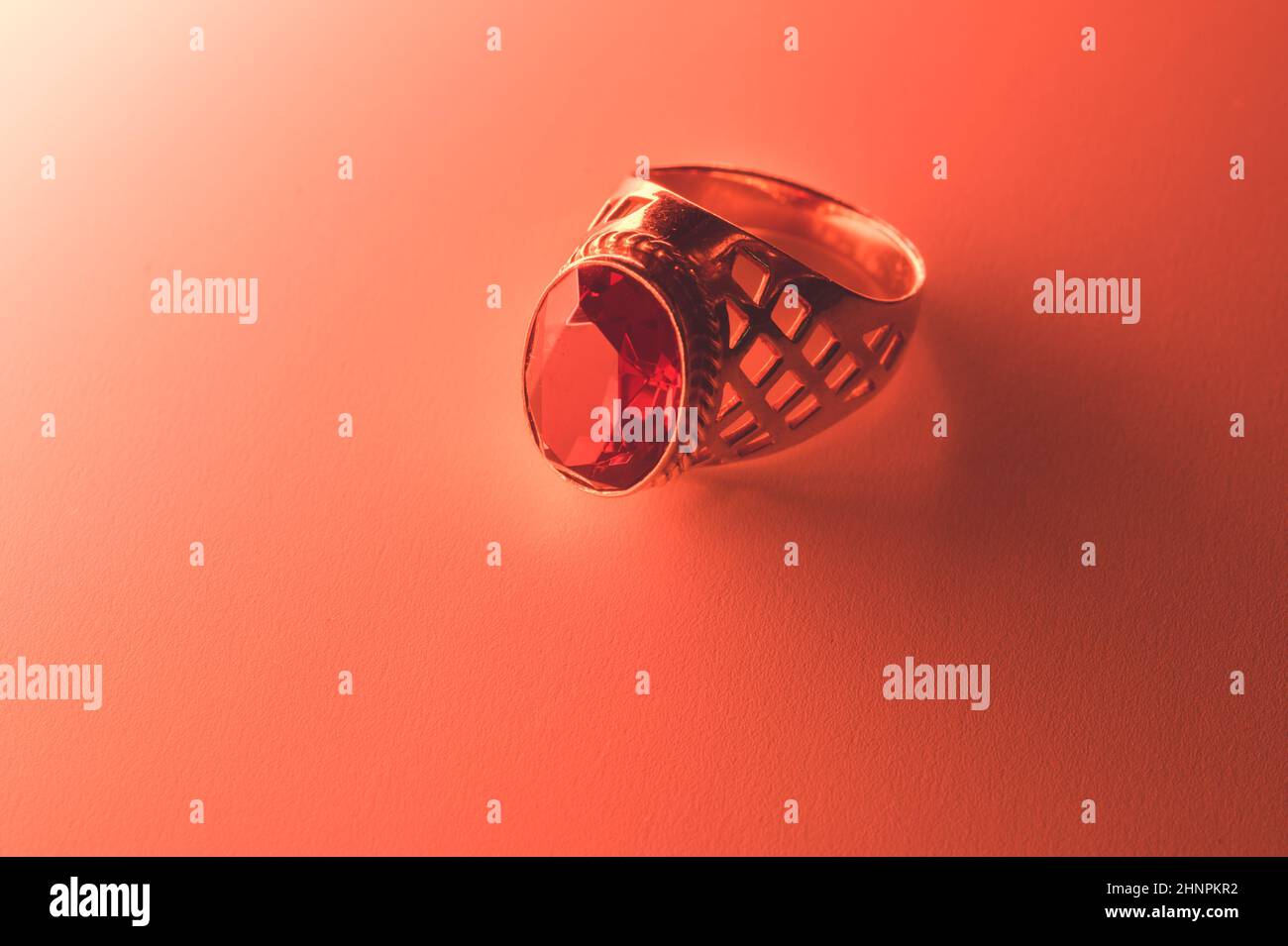 Golden ring with ruby under red light background Stock Photo - Alamy