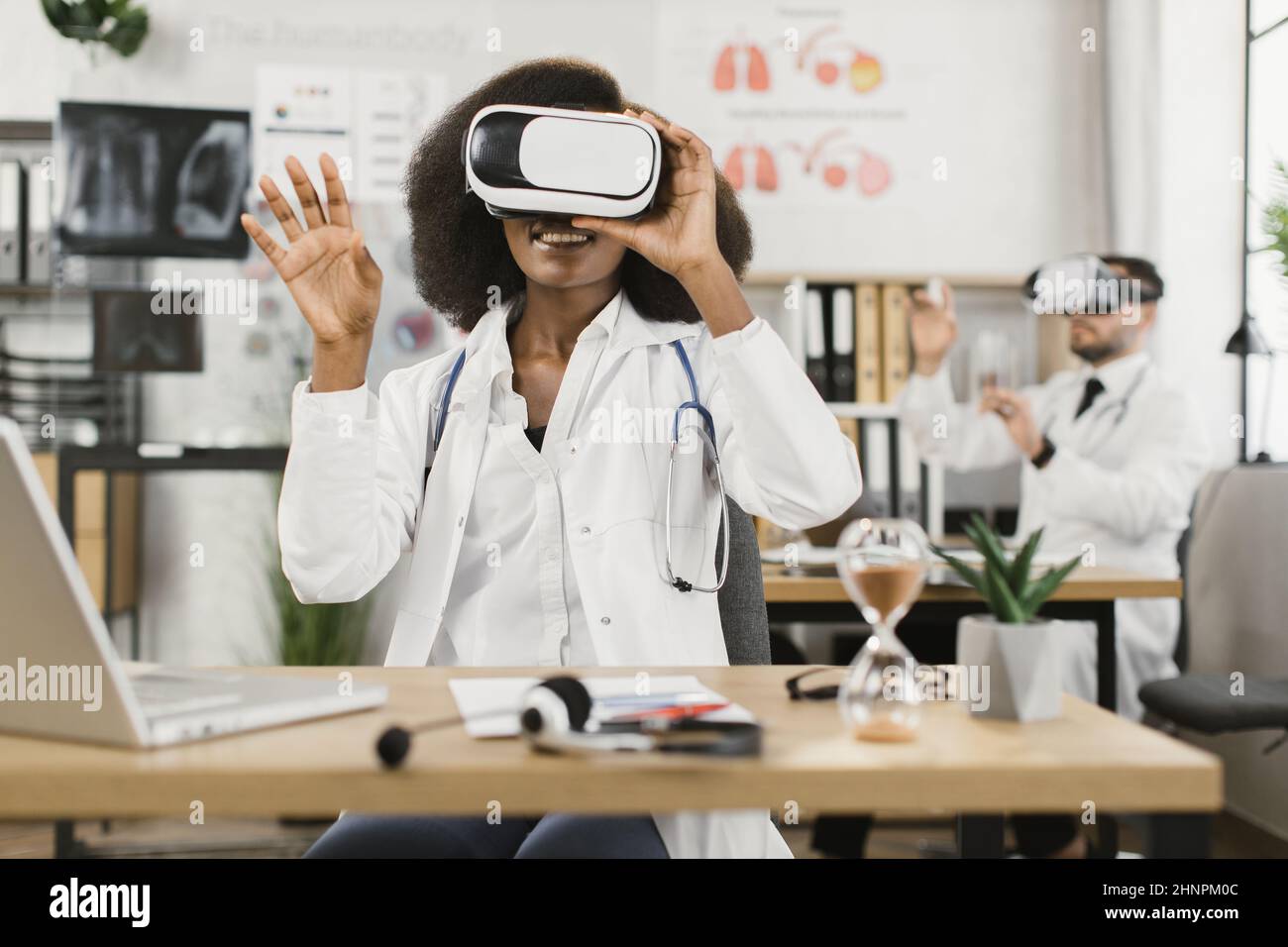 Two multicultural male and female doctors wearing VR goggles while ...
