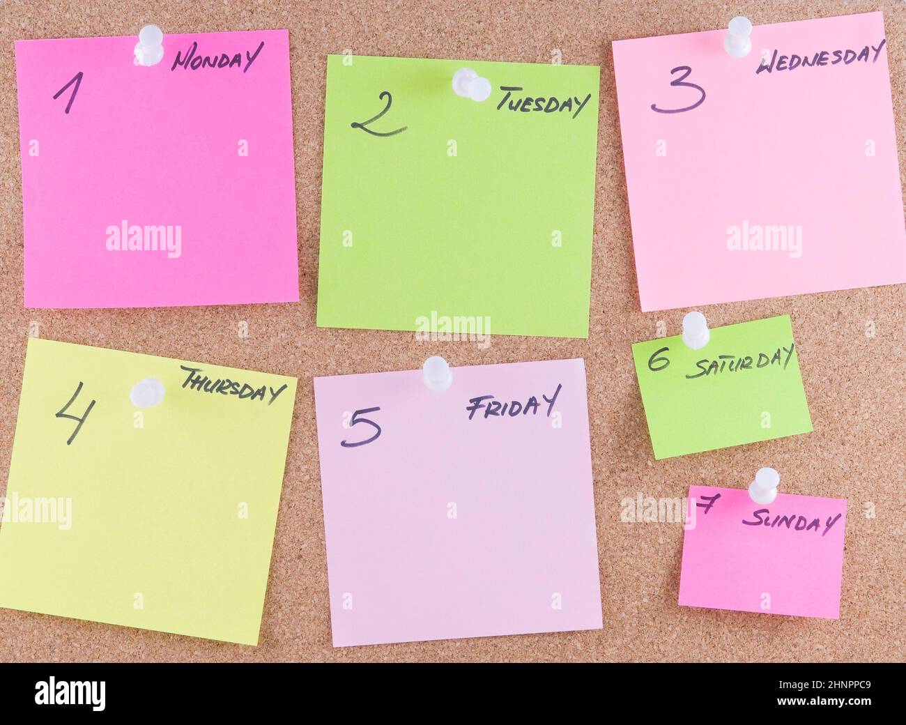 Colorful sticky notes attached to a corkboard with white thumbtacks ...