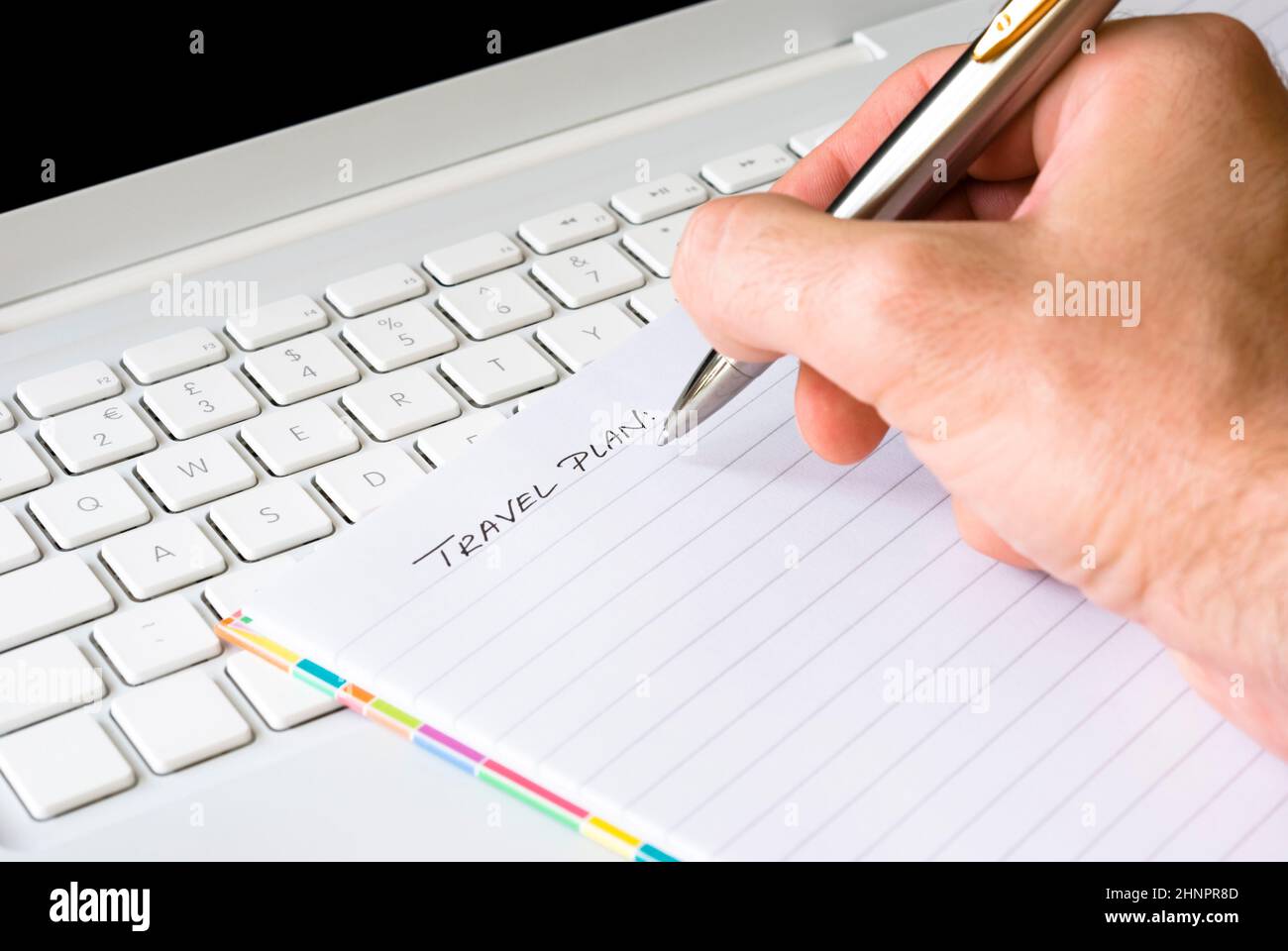 Hand writing travel plan with silver pen arranged on white laptop ...