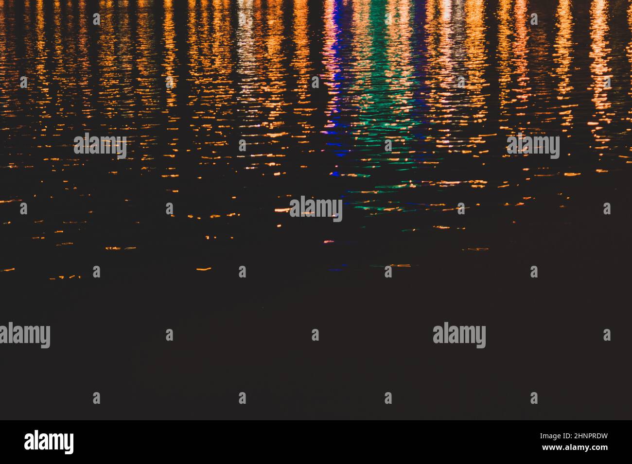 Blurred colorful lights reflect on water surface with ripples in the ...