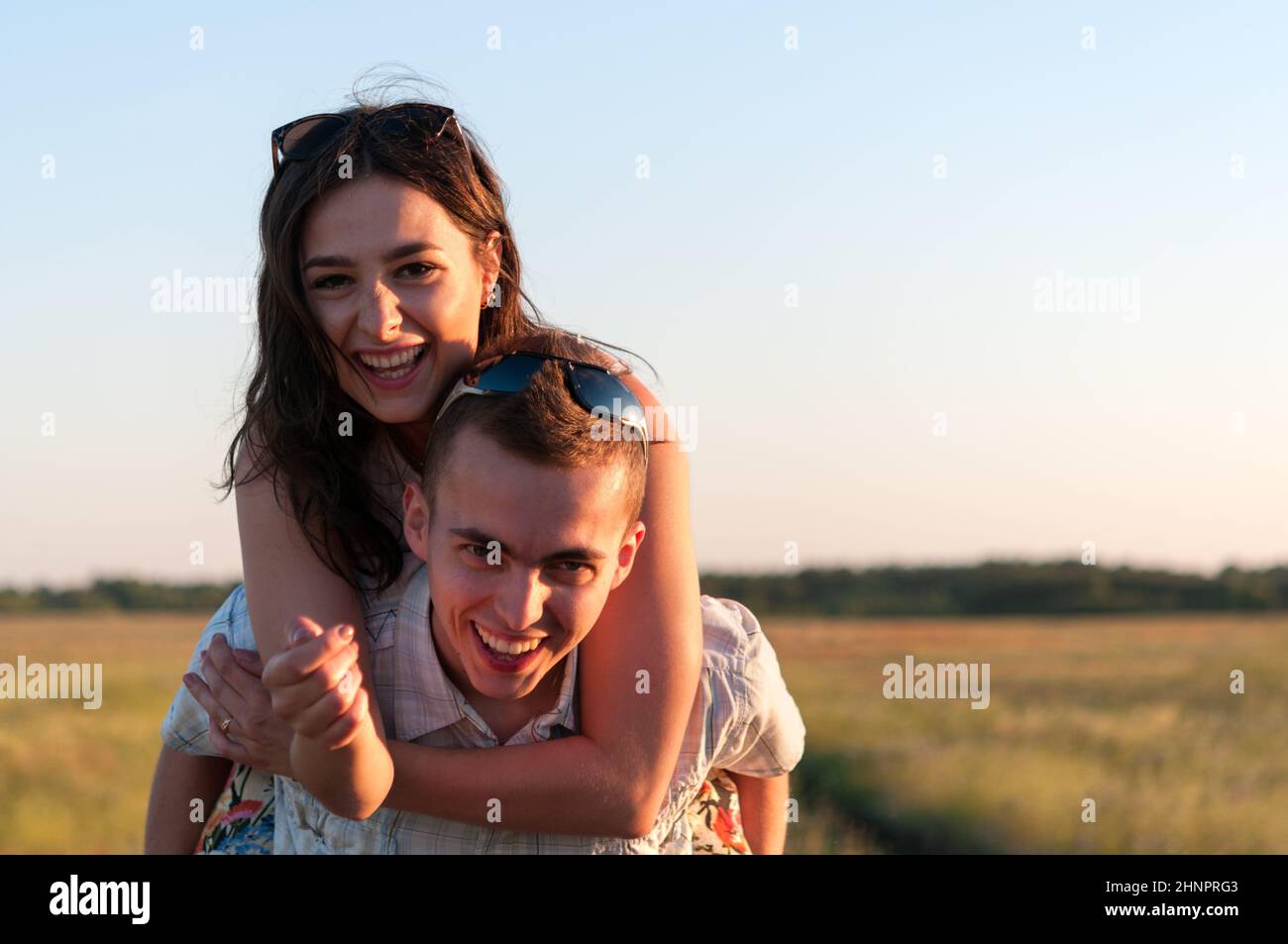 Young man carrying female friend on his back and having fun in the ...