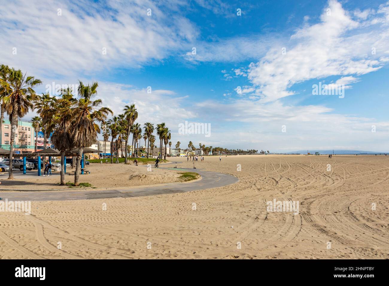 people enjoy scenic beach promenade with palms and colorful houses at ...