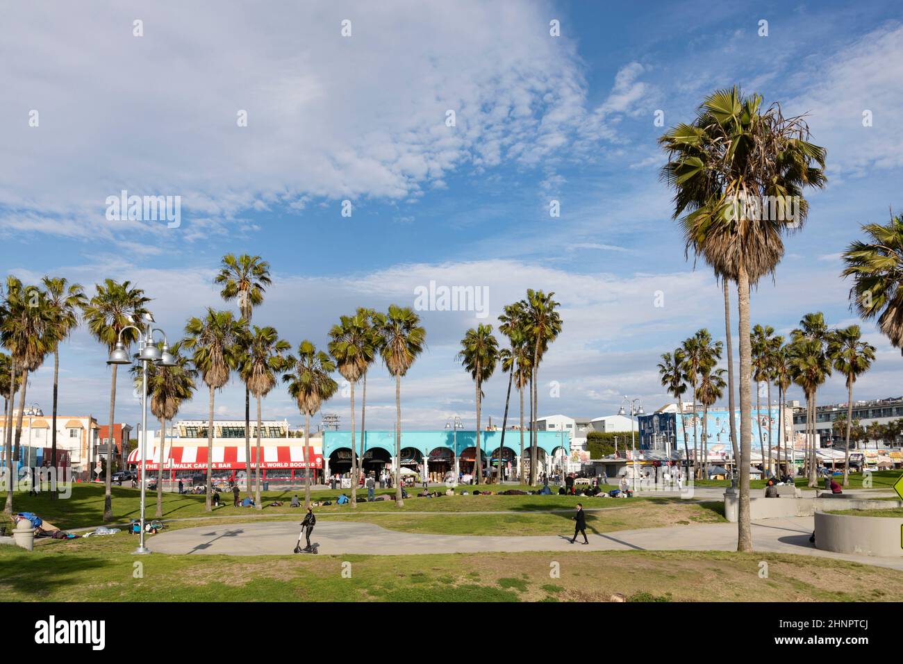 people enjoy scenic beach promenade with palms and colorful houses at ...