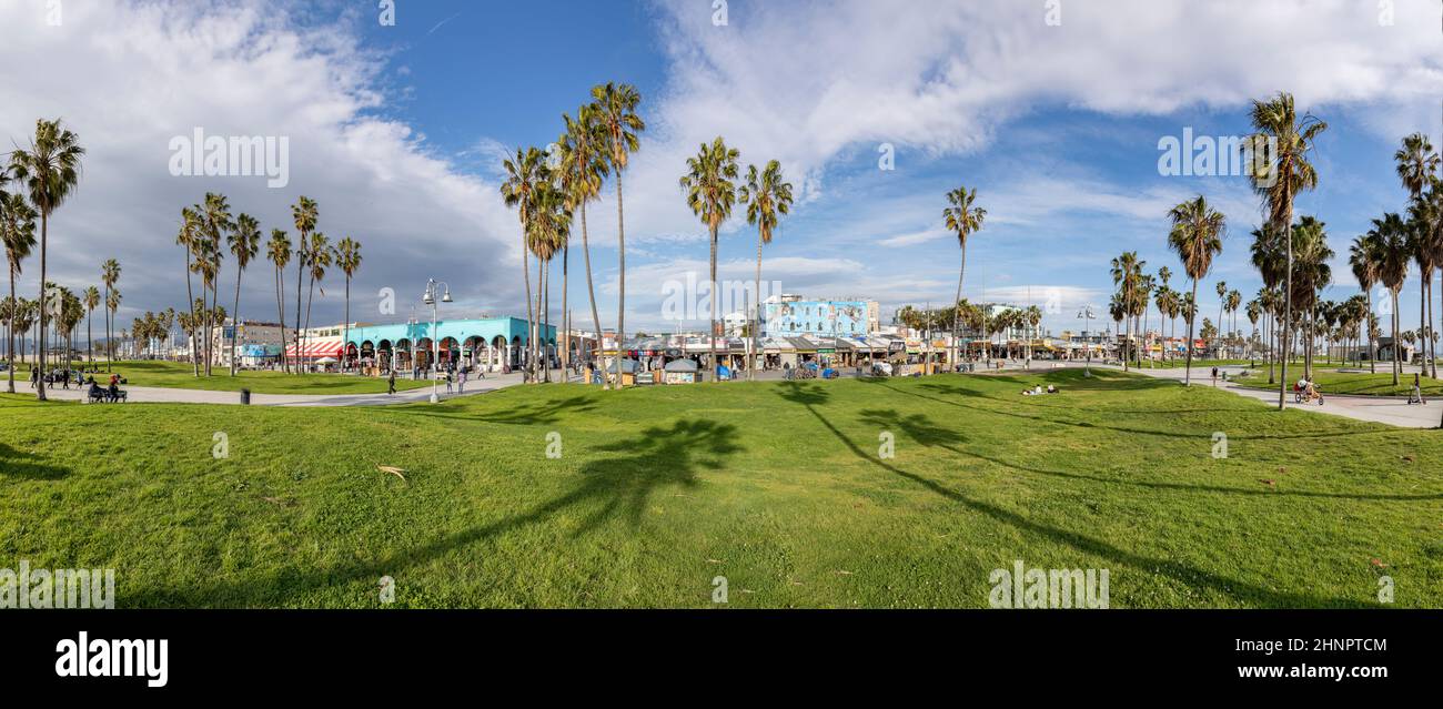 people enjoy scenic beach promenade with palms and colorful houses at ...