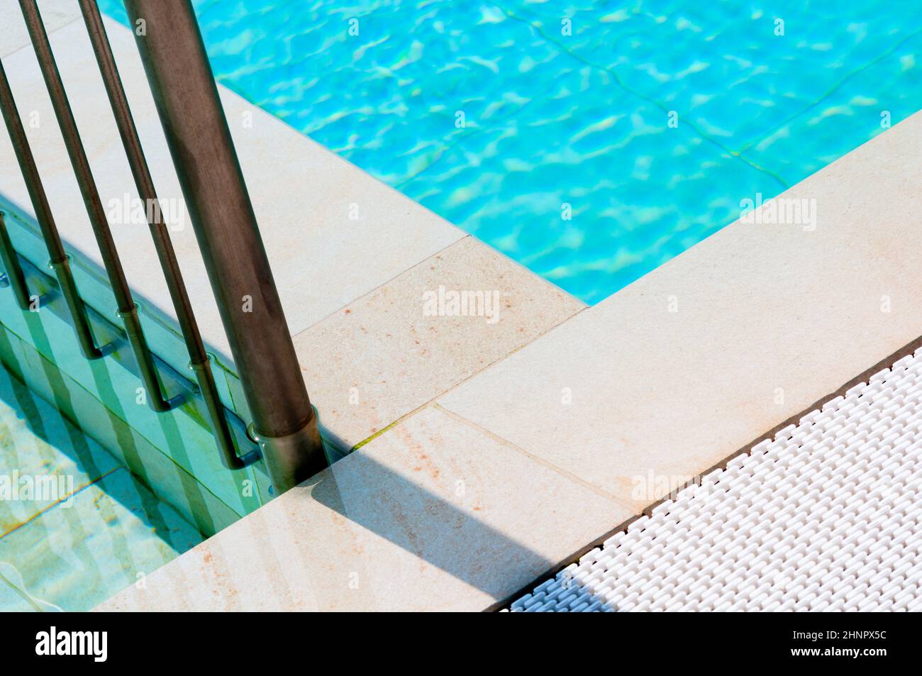 Details of swimming pool with turquoise water, tiles and steel railings ...