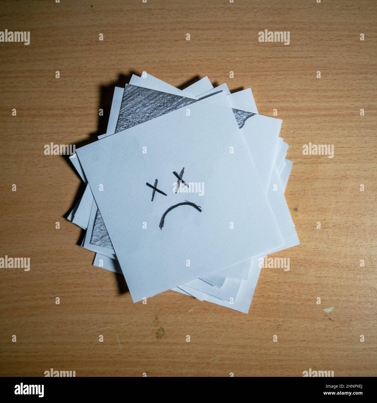 Stack of white papers with a drawing of a sad face Stock Photo - Alamy