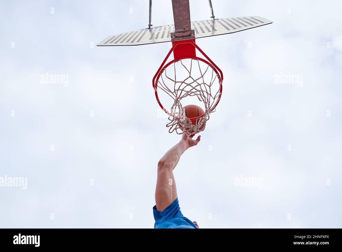 young Caucasian man dunking on an outdoor basketball court. concept of ...