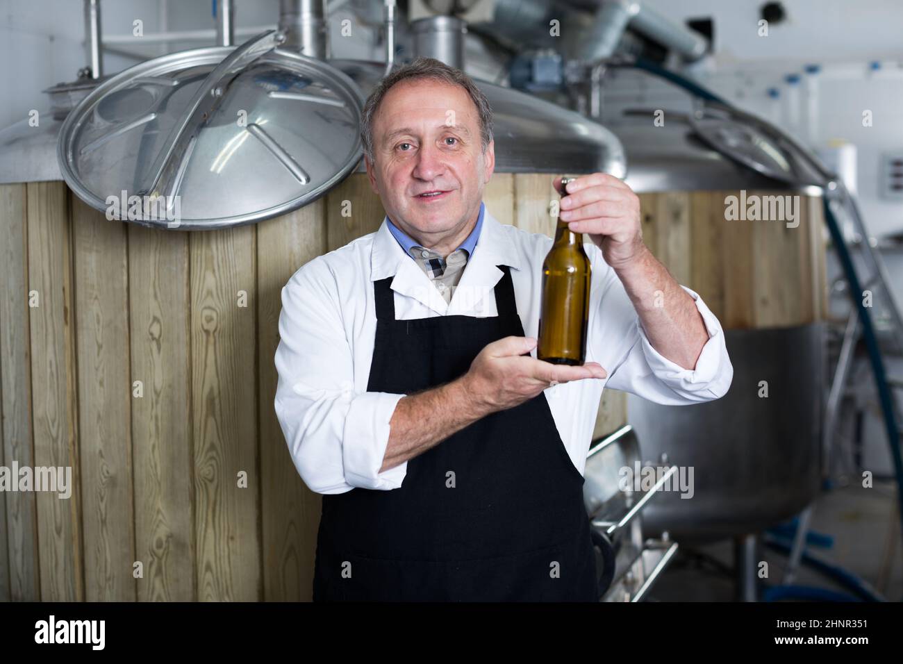 Adult brewer is standing with beer bottle Stock Photo - Alamy
