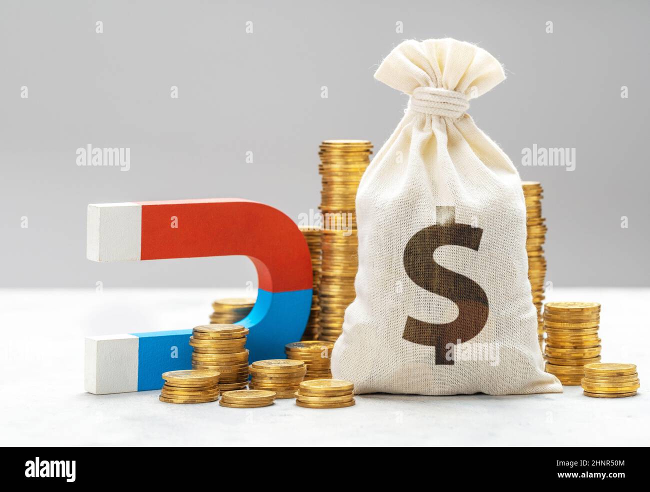 Magnet attracts money. Magnet and a stack of coins with money bag Stock ...