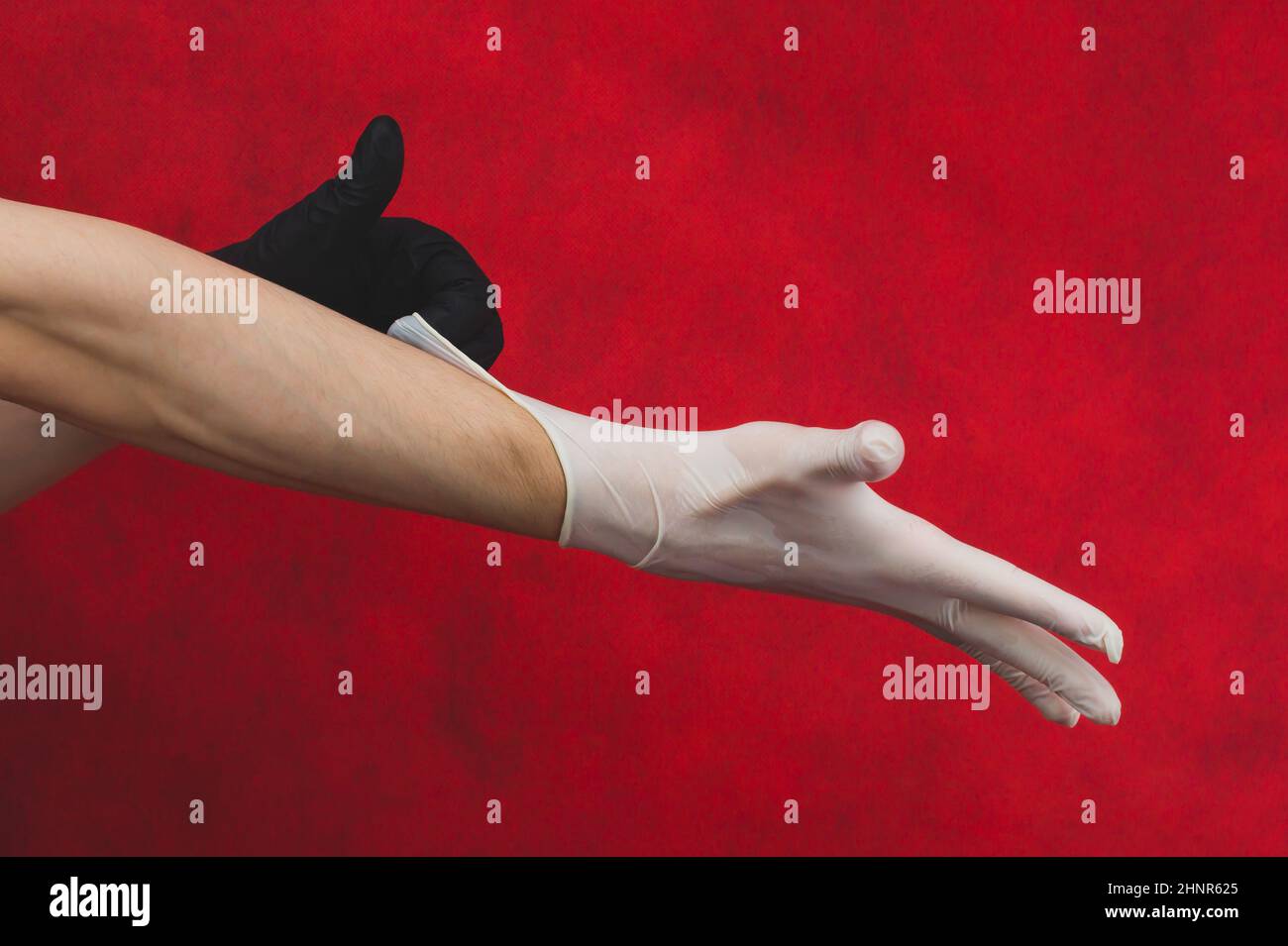 Hand in the black glove puts the white glove on the other. person puts ...