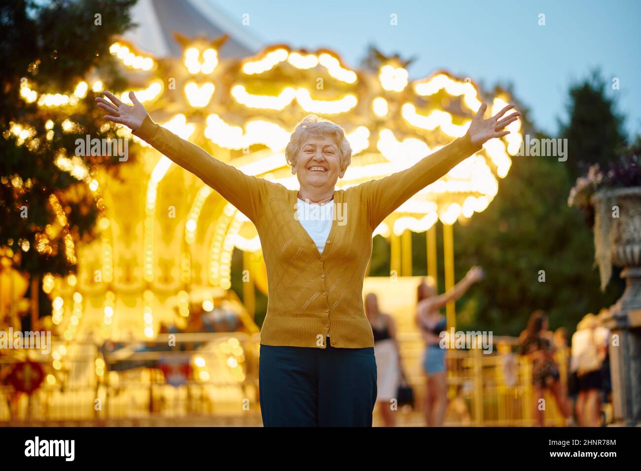 Pretty granny poses in summer amusement park, bright illumination on ...