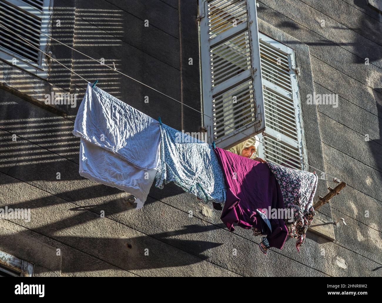 woman with scarf pegs out the washing on a washing line in front of the ...
