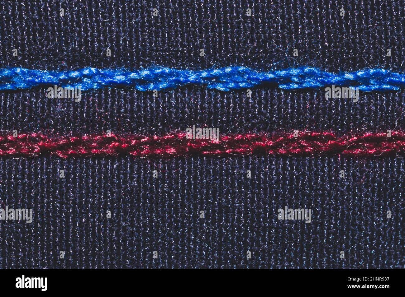Blue and red seam on black fabric. stitches on textile material close ...