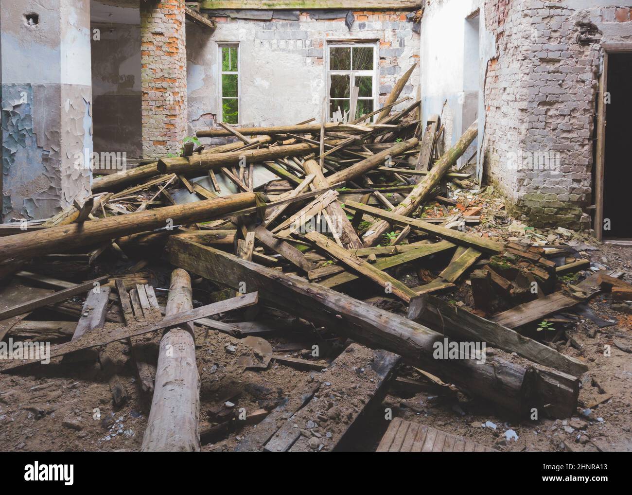 Ruined interior of old abandoned building. wooden logs of broken roof ...