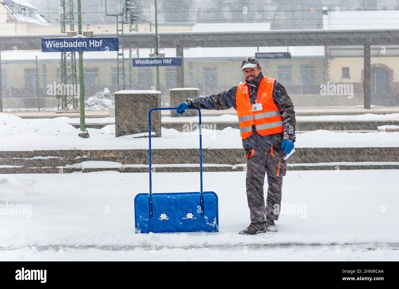 Worker is cleaning the train platform from snow in heavy snowstorm ...