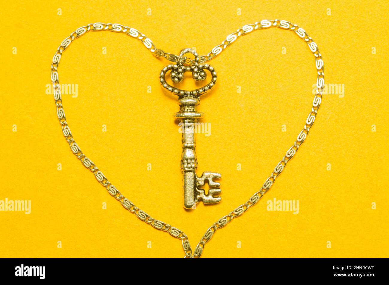 Old key with the chain isolated on yellow background. safety and ...