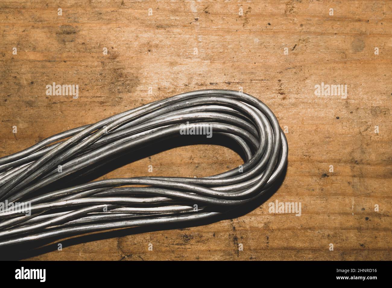 Grey wire on a wood background. wire without braiding lies on the ...