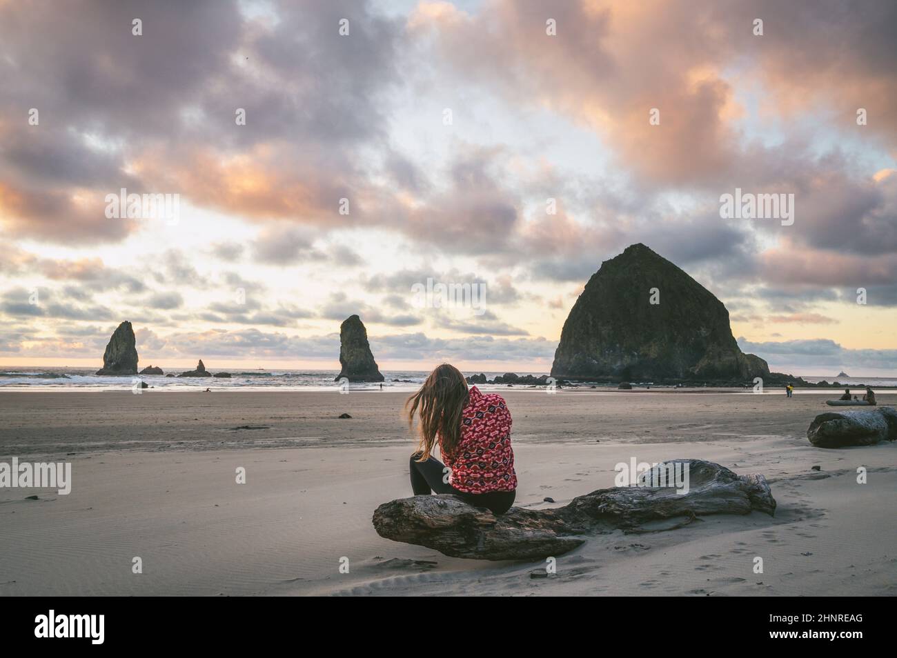 Female sitting on the beach at sunset on the Oregon Coast Stock Photo ...