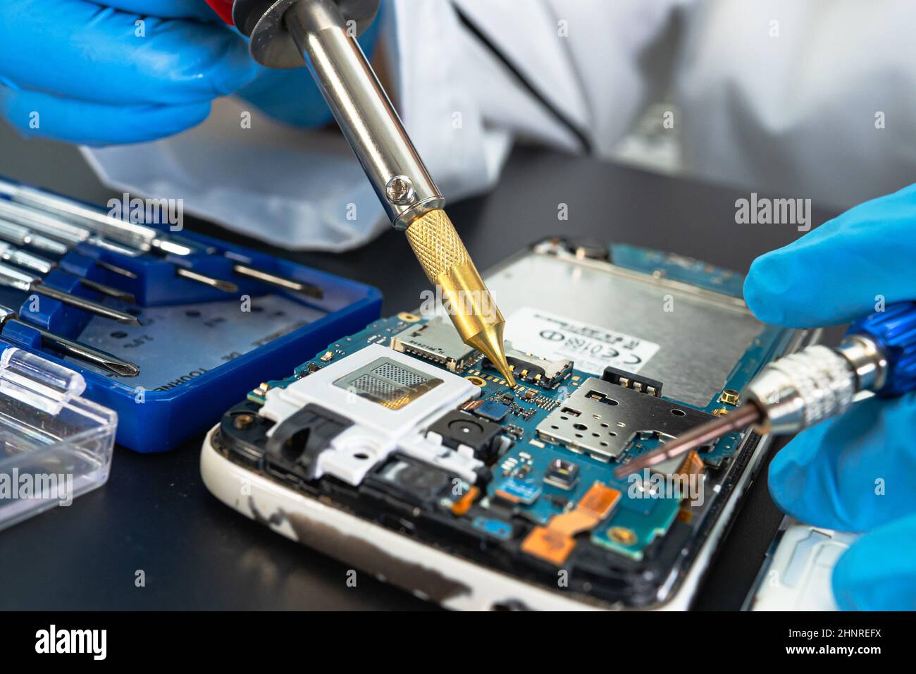 Technician repairing inside of mobile phone by soldering iron ...