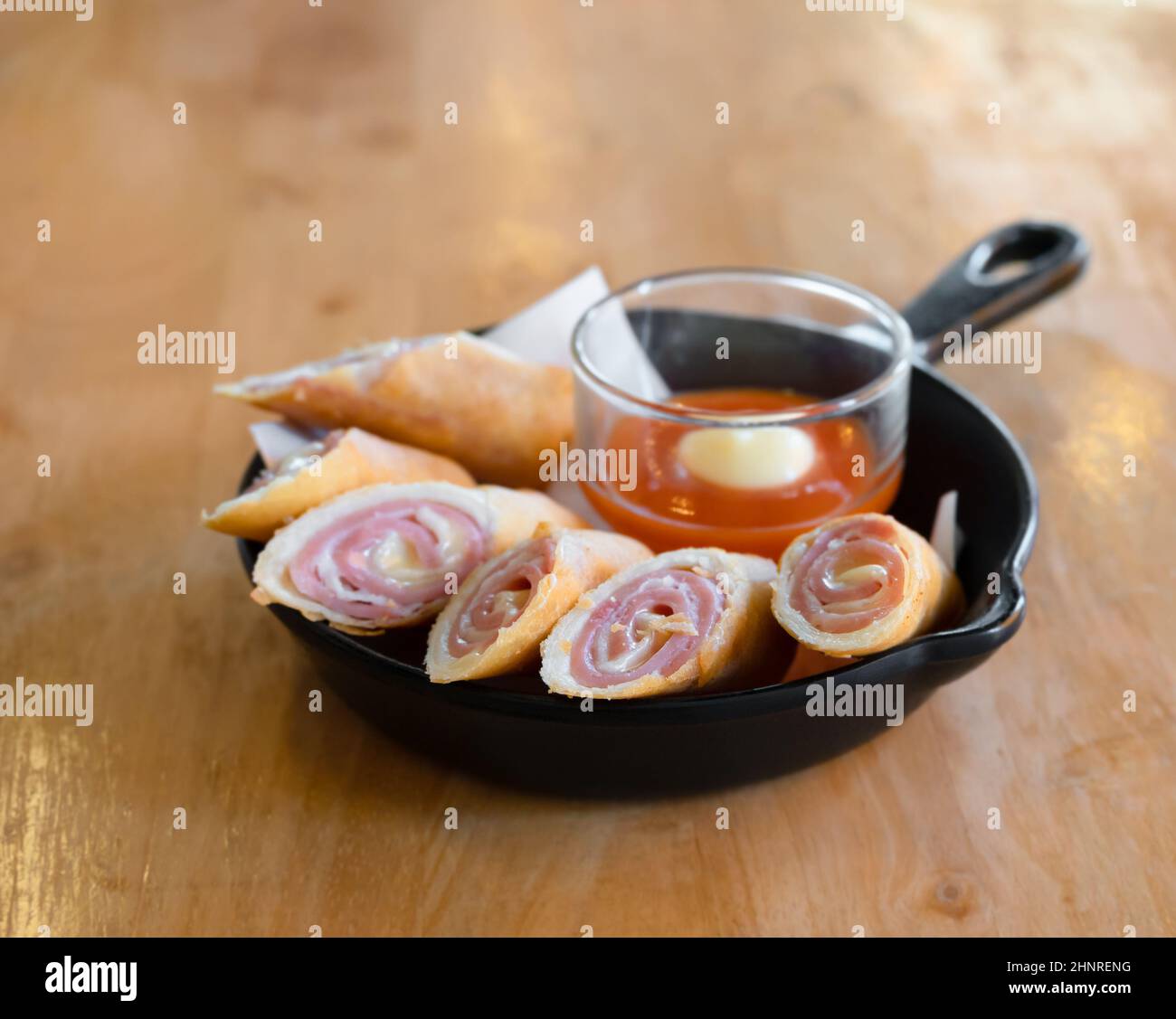 Fried ham and cheese spring rolls served with hot chilli sauce on black ...
