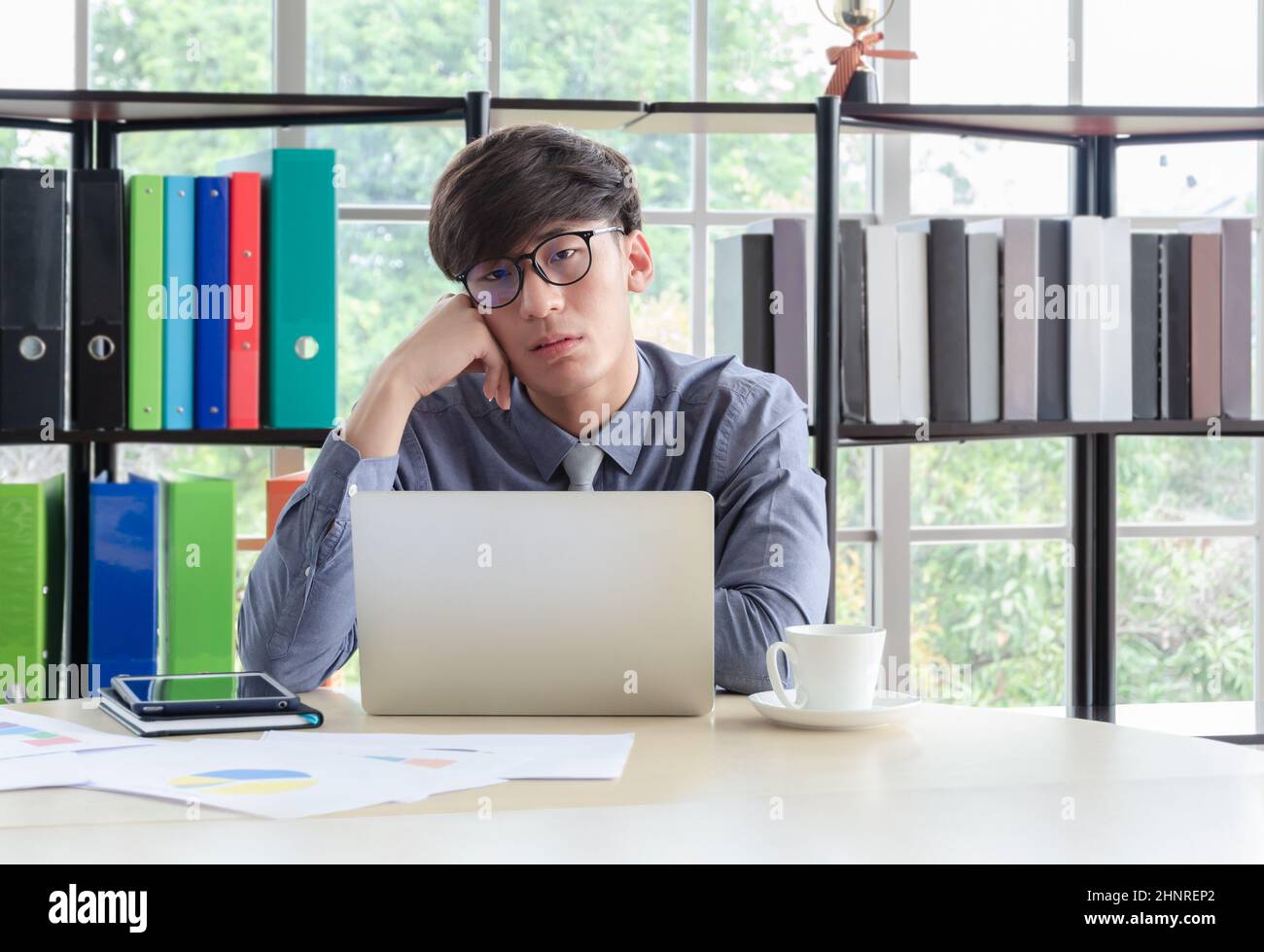 Young sleepy businessman wearing glasses sitting and holding head on ...