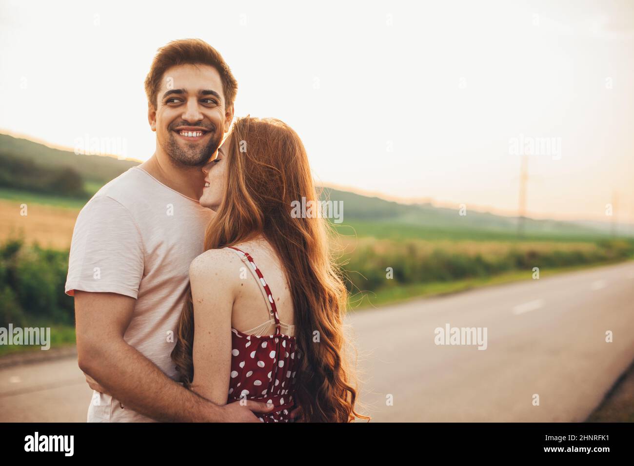 Shot of an affectionate smiling man embracing girlfriend in the middle ...