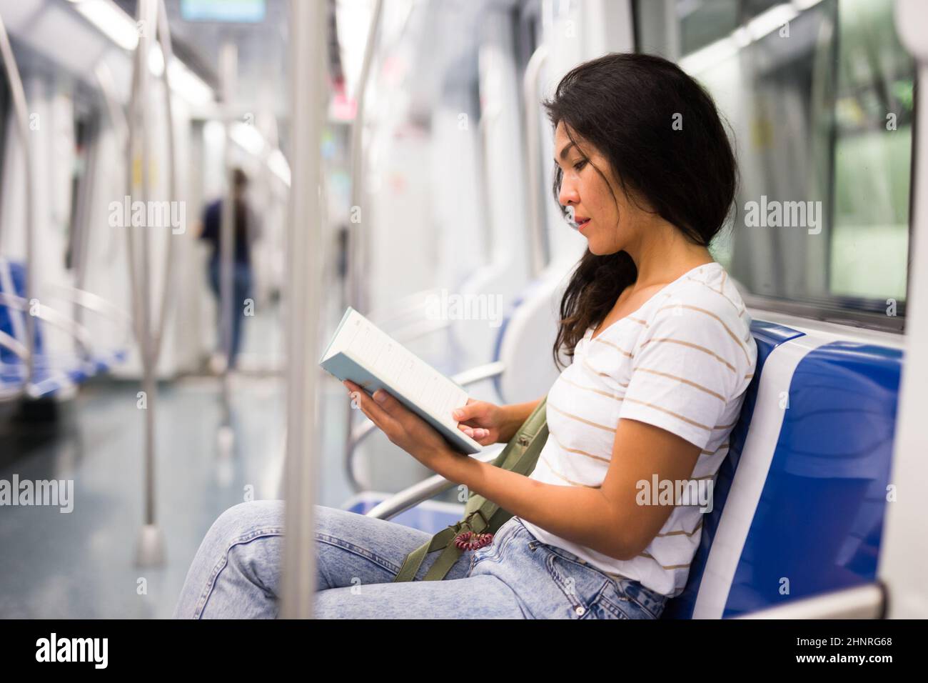 Woman reading book in subway train Stock Photo - Alamy